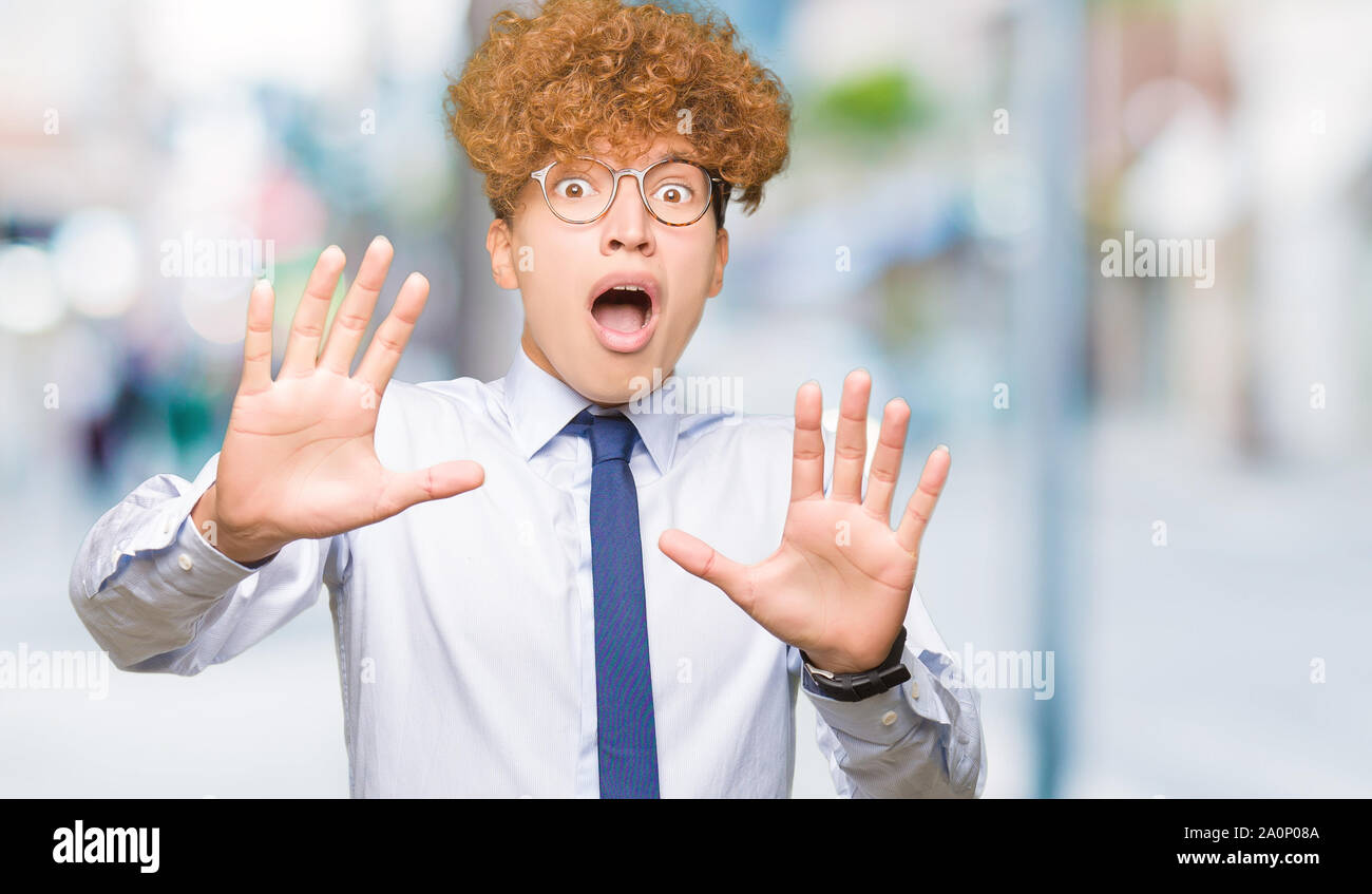 Young handsome business man with afro wearing glasses afraid and ...