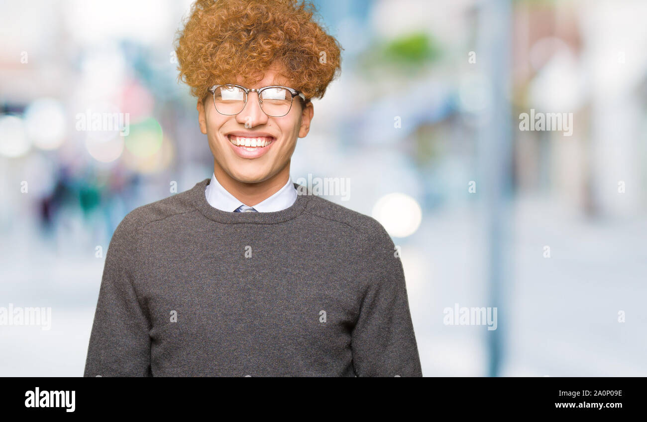 Young handsome business man with afro hair wearing glasses with a happy ...
