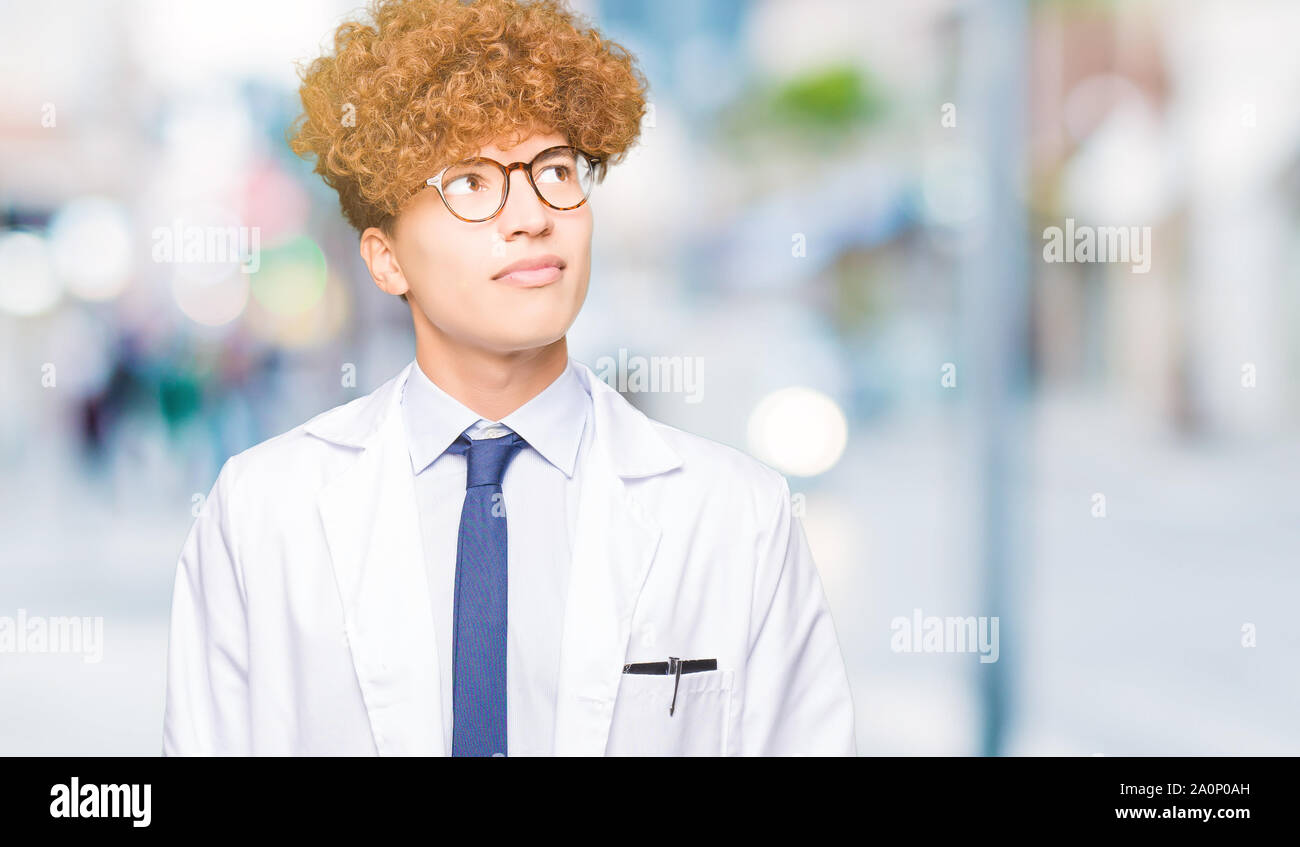 Young handsome scientist man wearing glasses smiling looking side and ...