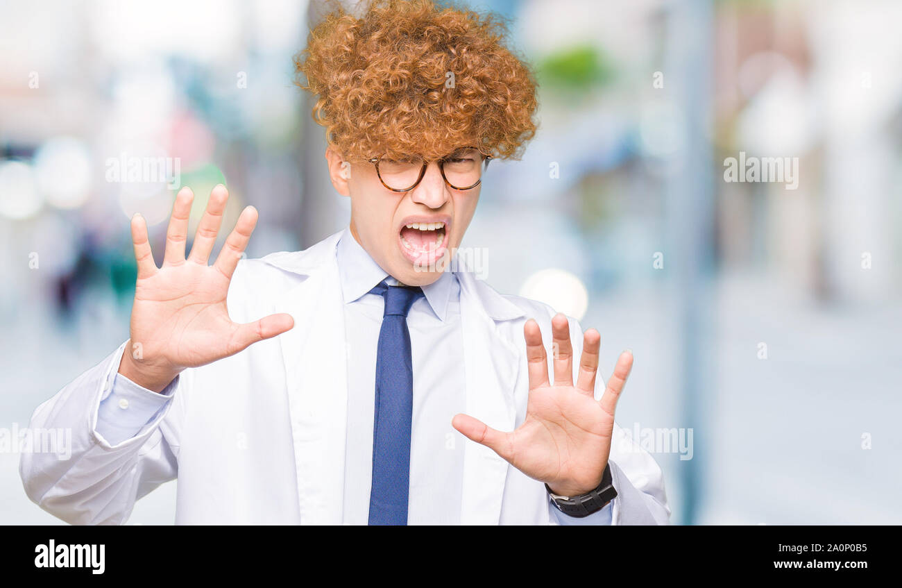 Young handsome scientist man wearing glasses afraid and terrified with ...