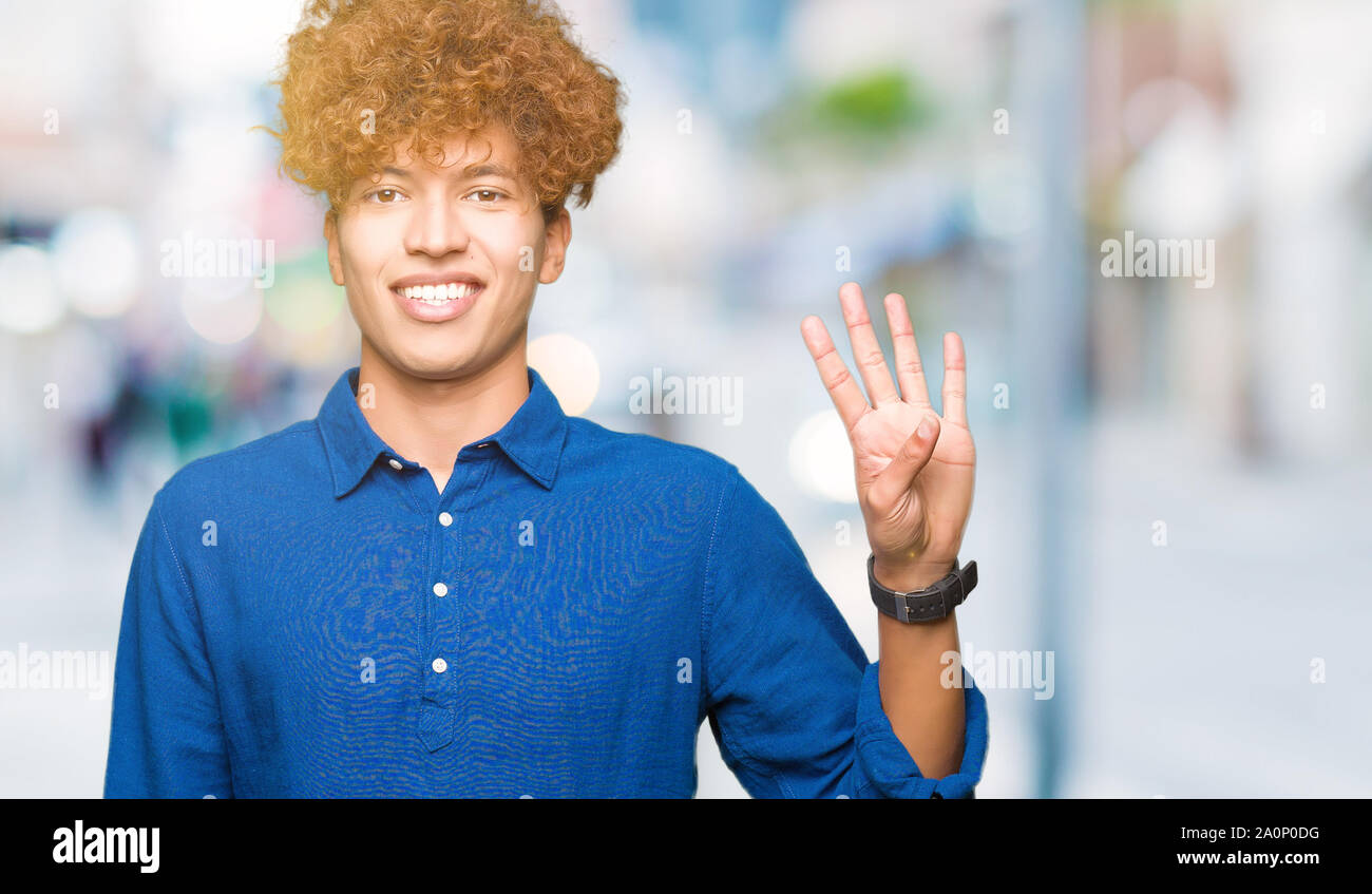 Young handsome elegant man with afro hair showing and pointing up with ...
