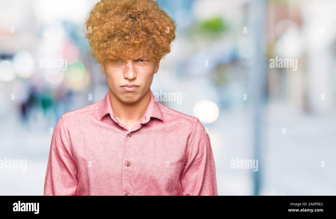 Young handsome business man with afro hair skeptic and nervous ...