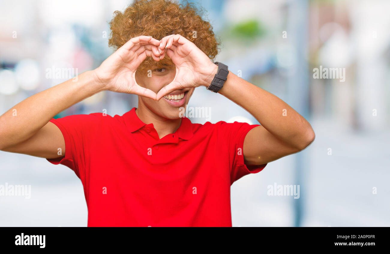 Young handsome man with afro hair wearing red t-shirt Doing heart shape ...