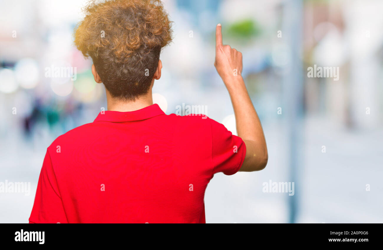 Young handsome man with afro hair wearing red t-shirt Posing backwards ...