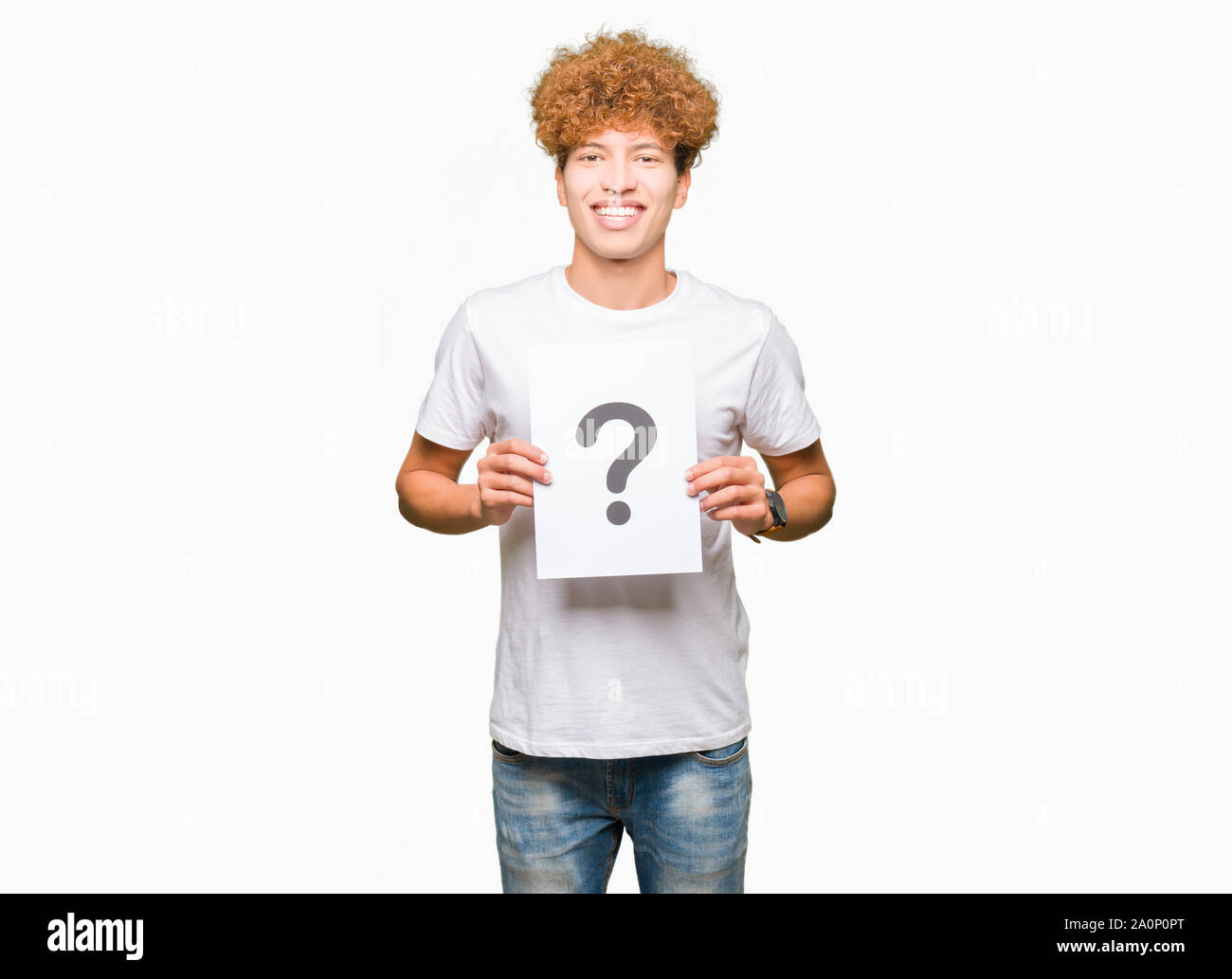 Young handsome man holding paper with question mark with a happy face ...