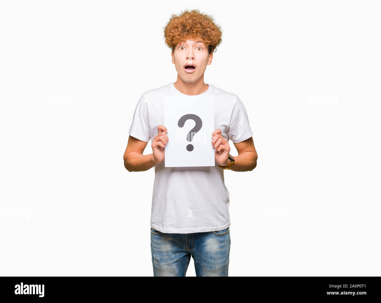Young handsome man holding paper with question mark scared in shock ...
