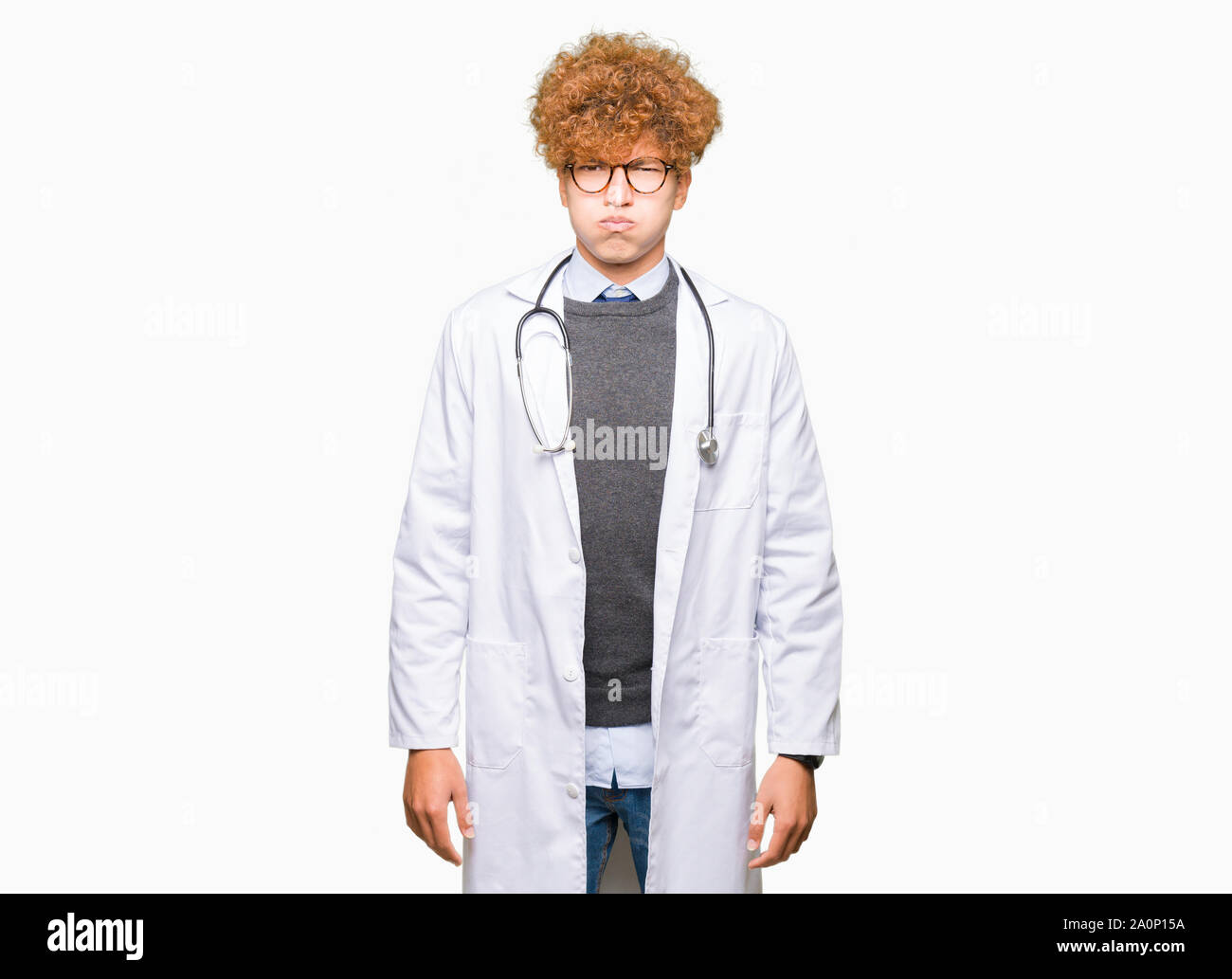 Young handsome doctor man wearing medical coat puffing cheeks with ...