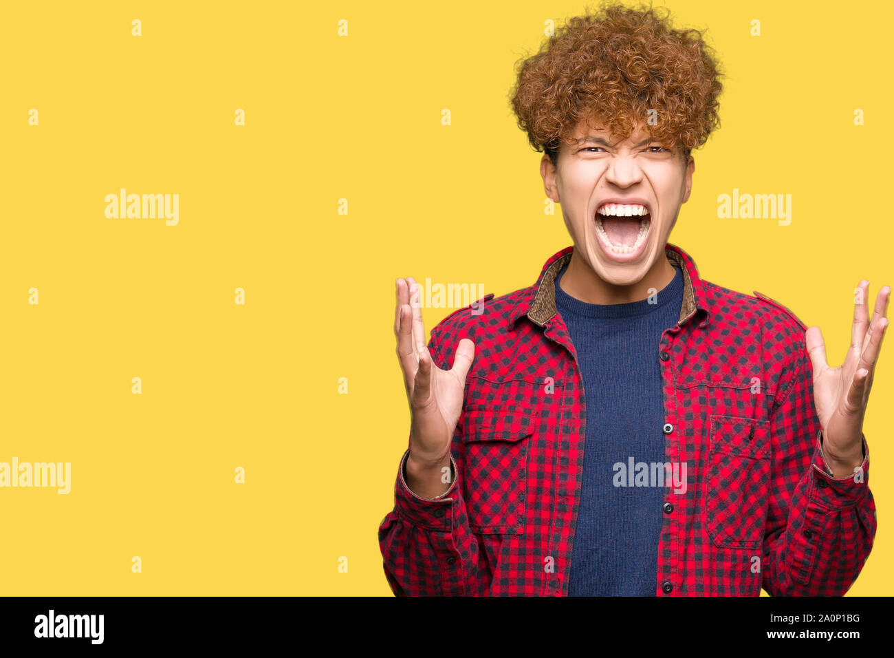 Young handsome student man with afro hair wearing a jacket crazy and ...