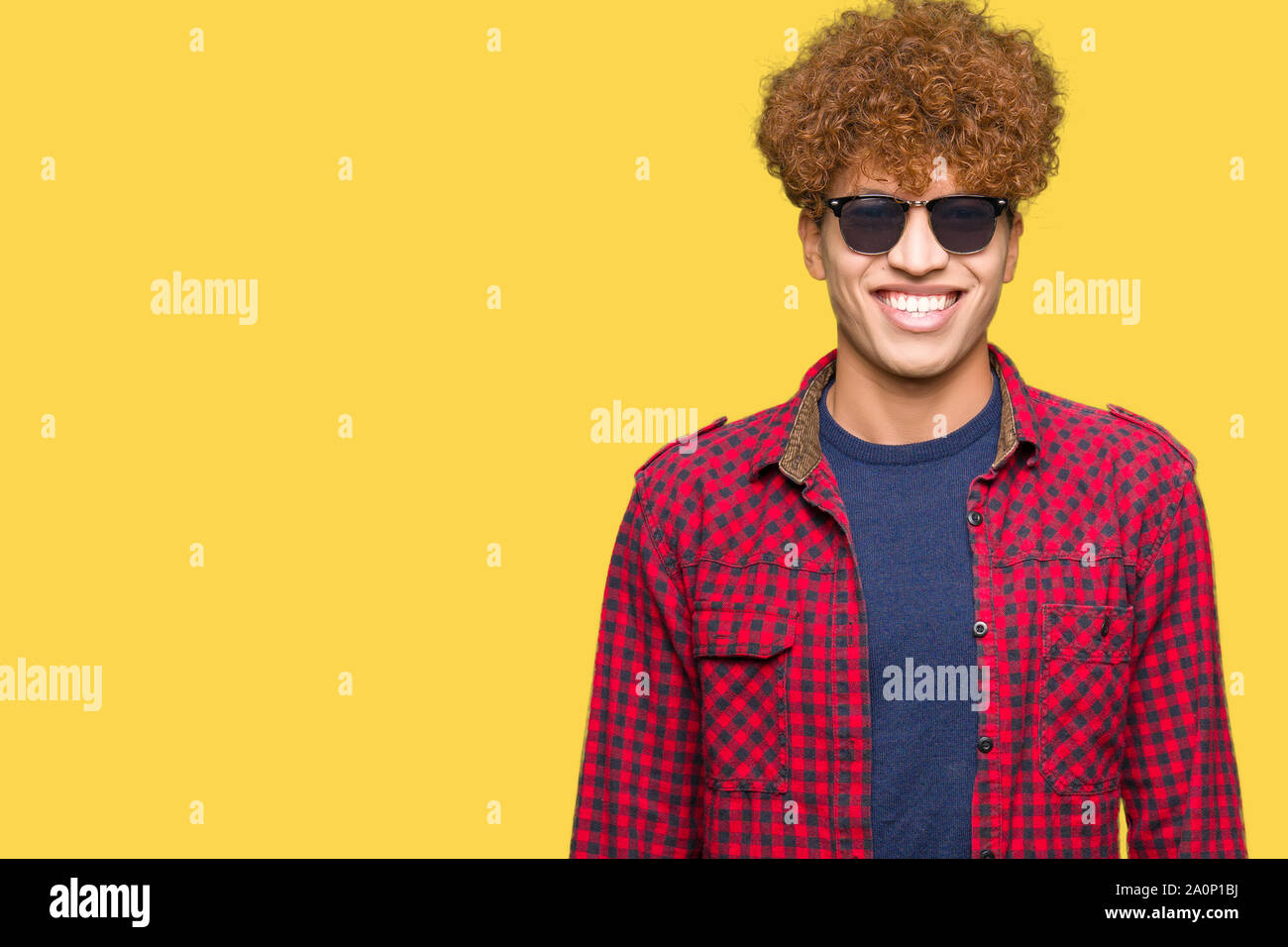 Young handsome man with afro hair wearing sunglasses with a happy and ...