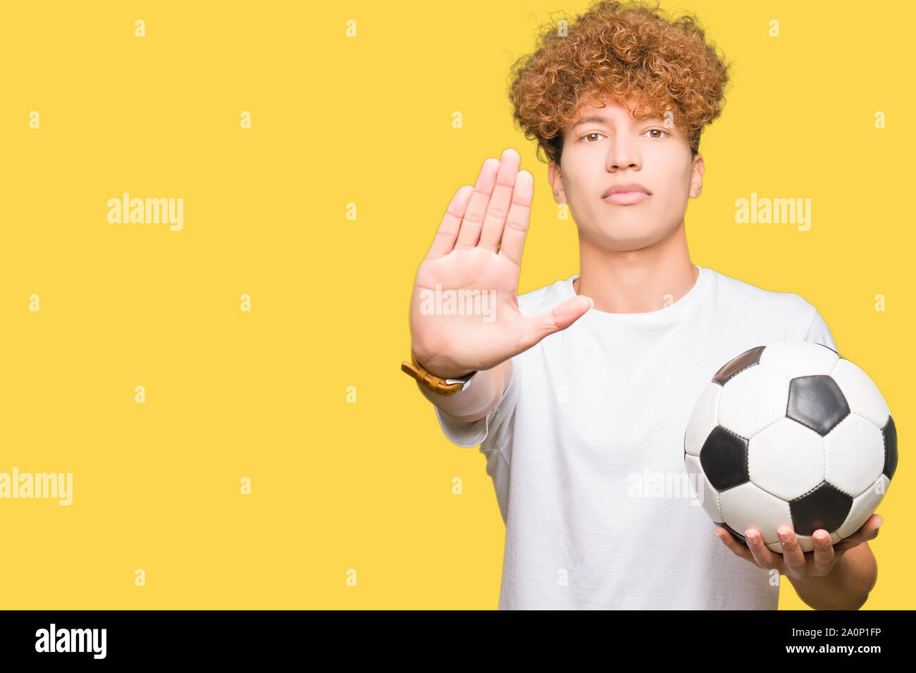 Young handsome man holding soccer football ball with open hand doing ...