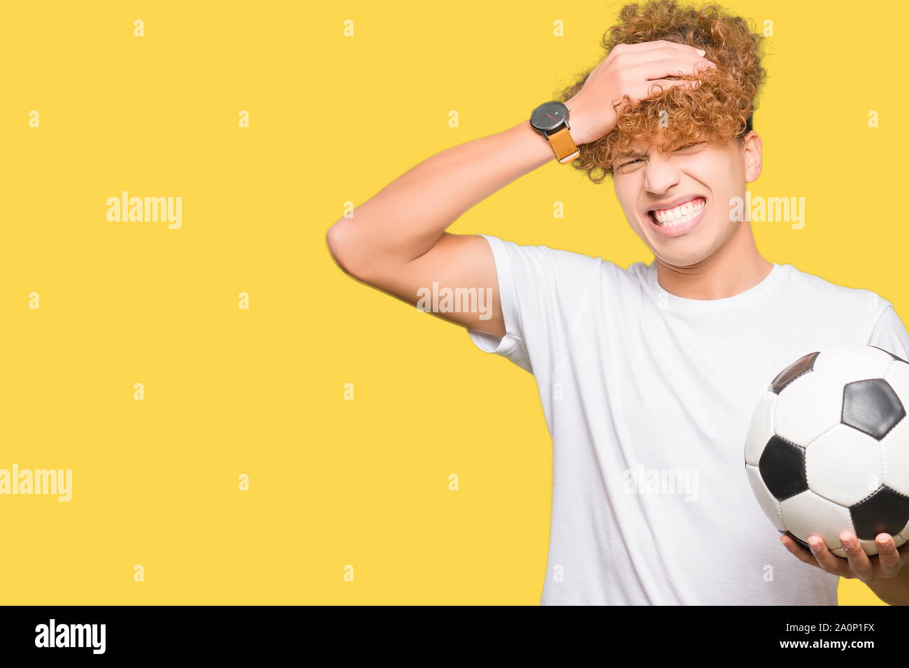 Young handsome man holding soccer football ball stressed with hand on ...