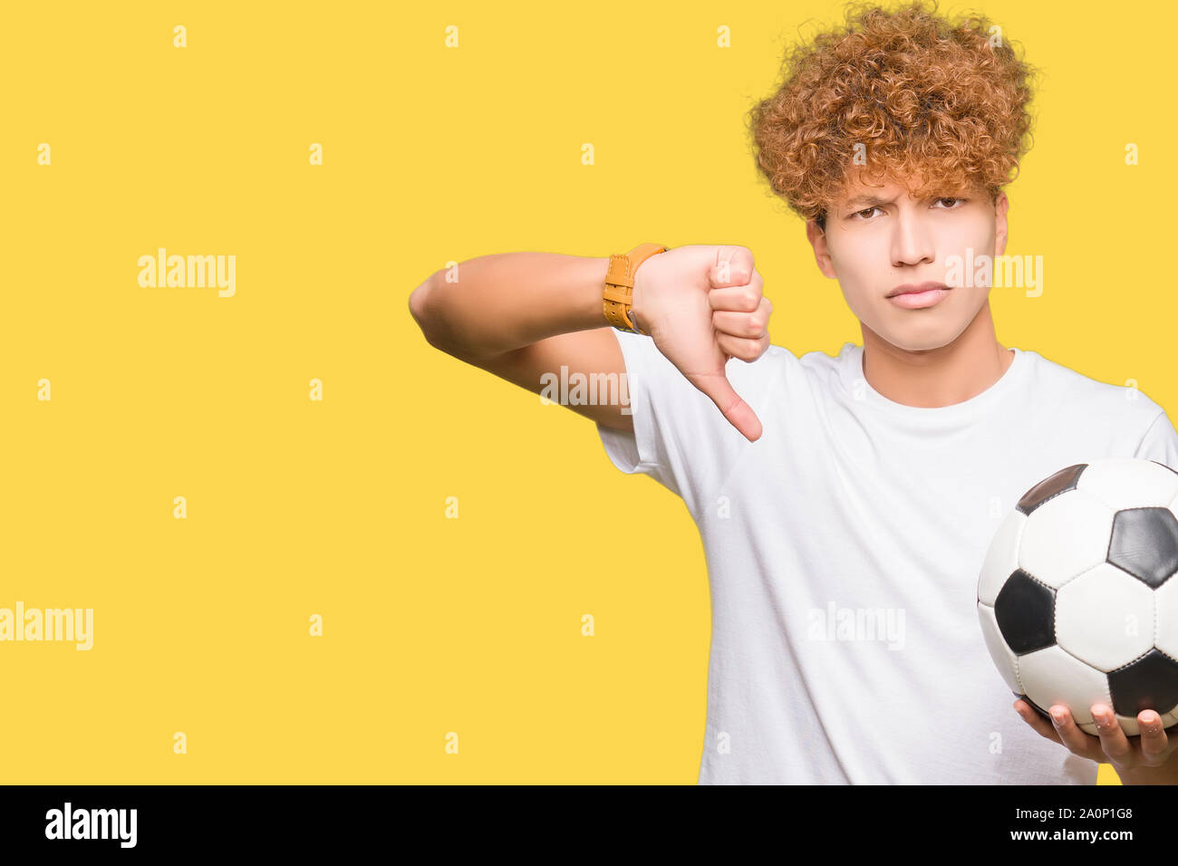 Young handsome man holding soccer football ball with angry face ...