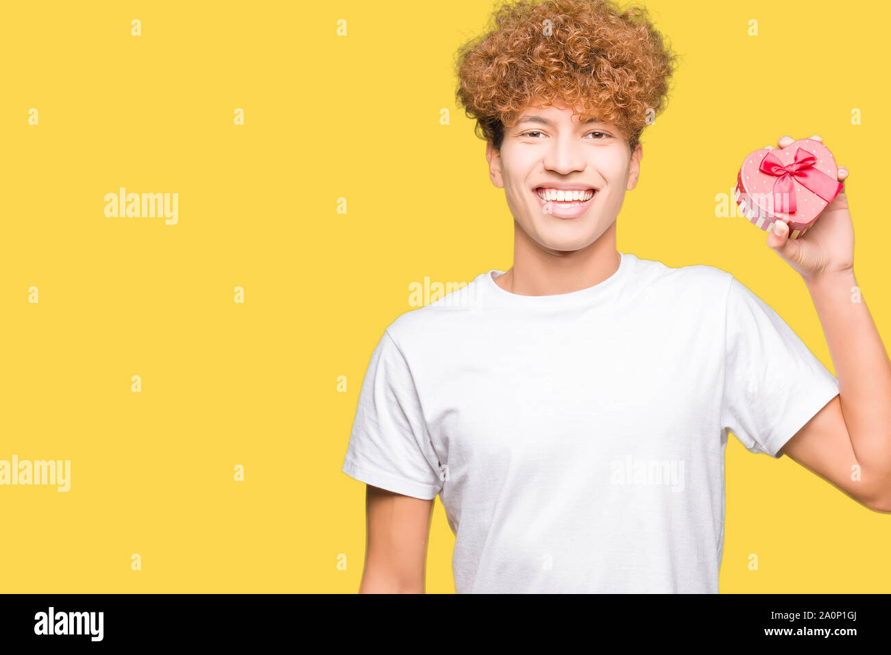 Young handsome man holding heart box as gift of valentine's day with a ...