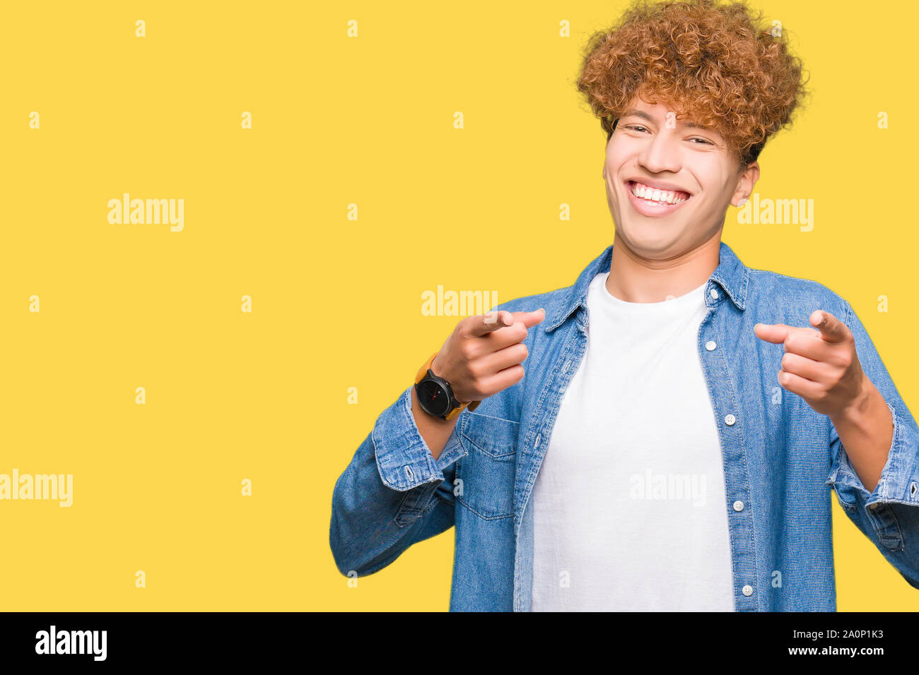 Young handsome man with afro hair wearing denim jacket pointing fingers ...