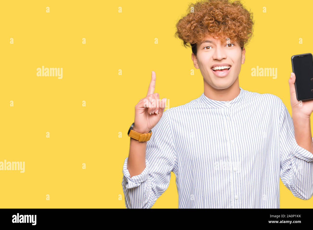 Young handsome man showing smartphone screen surprised with an idea or ...