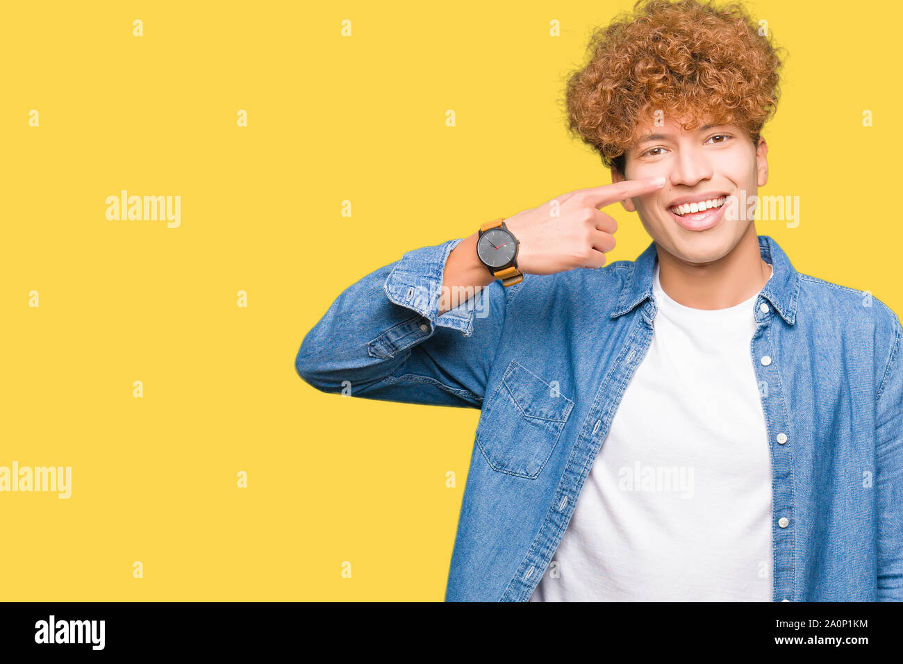 Young handsome man with afro hair wearing denim jacket Pointing with ...