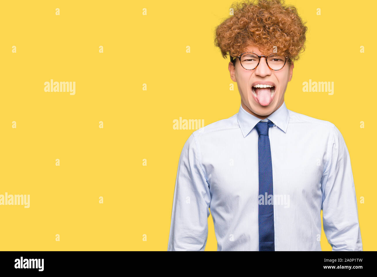 Young handsome business man with afro wearing glasses sticking tongue ...