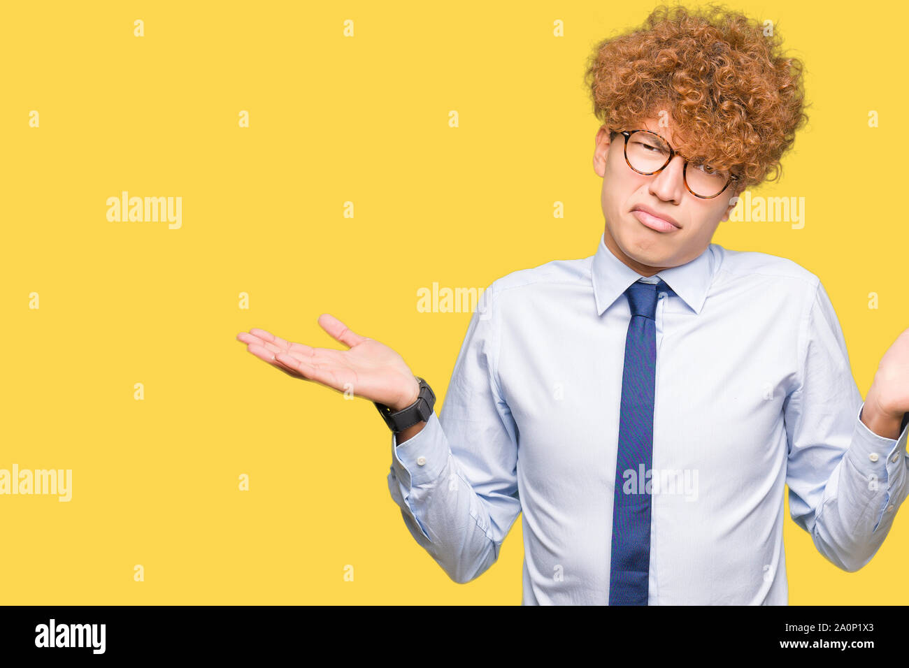 Young handsome business man with afro wearing glasses clueless and ...