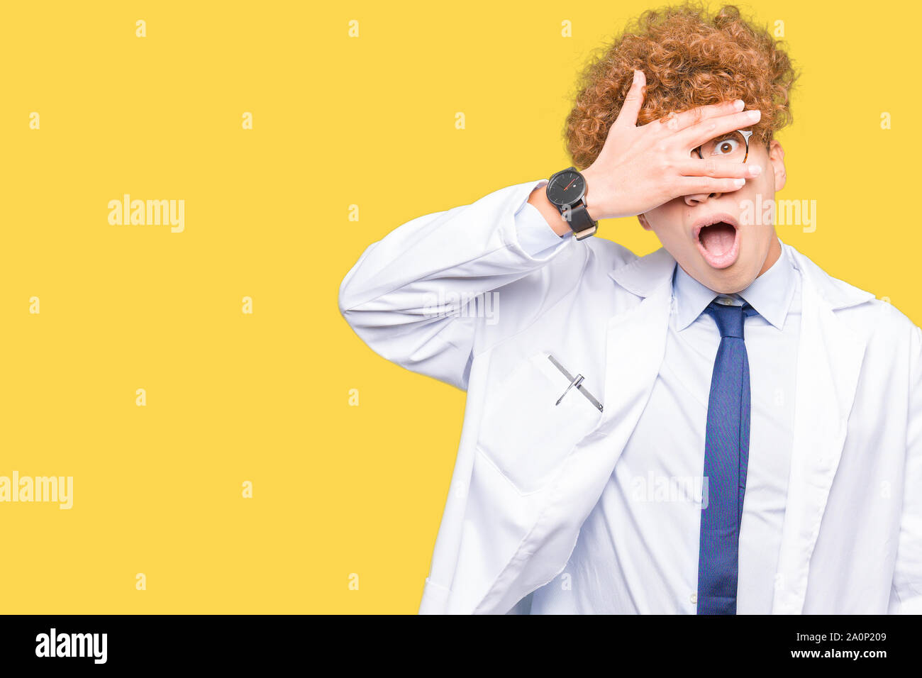 Young handsome scientist man wearing glasses peeking in shock covering ...