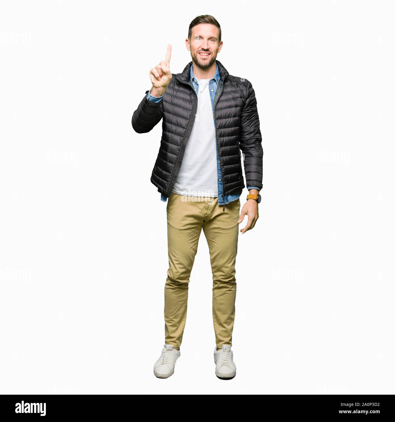 Handsome man wearing winter coat showing and pointing up with finger ...