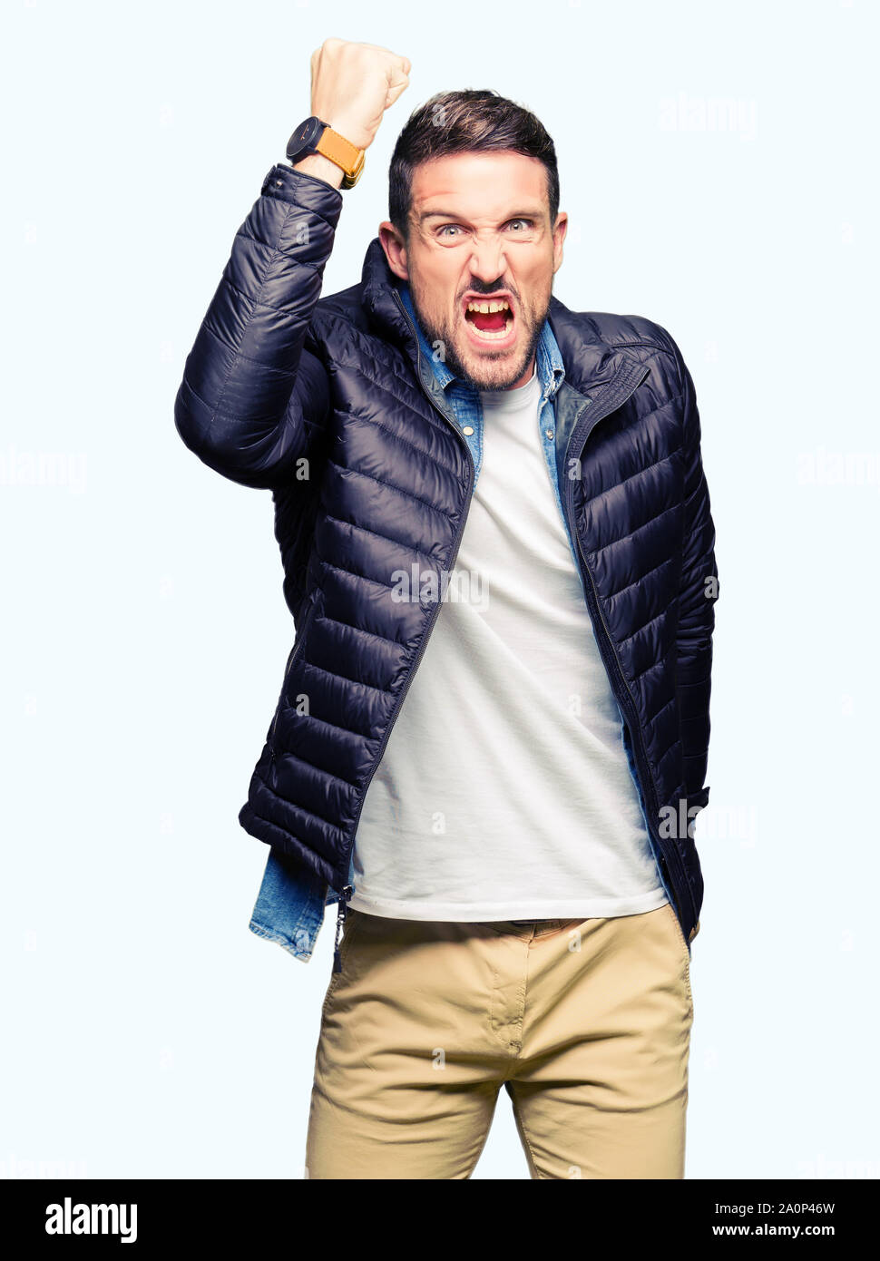 Handsome man wearing winter coat angry and mad raising fist frustrated ...