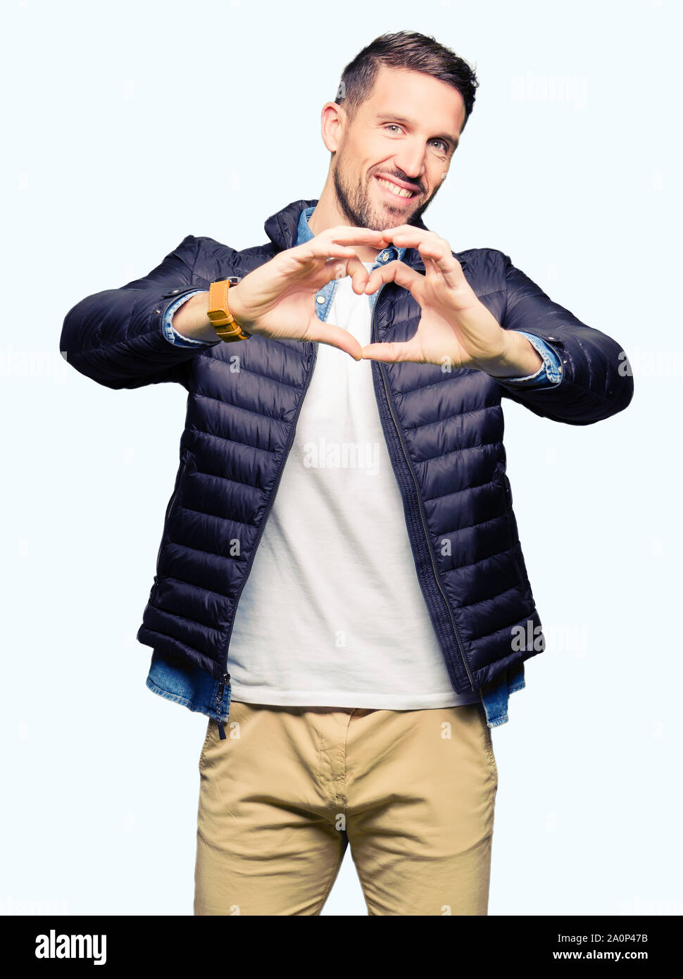 Handsome man wearing winter coat smiling in love showing heart symbol ...
