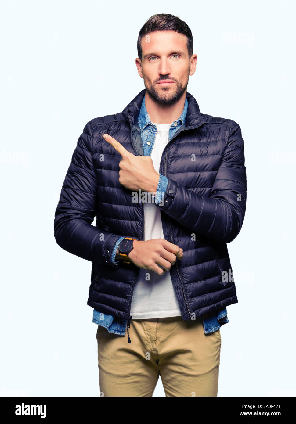 Handsome man wearing winter coat Pointing with hand finger to the side ...