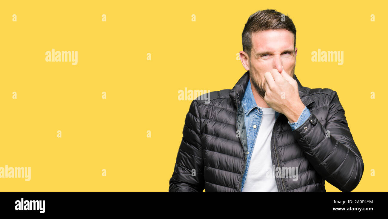 Handsome man wearing winter coat smelling something stinky and ...