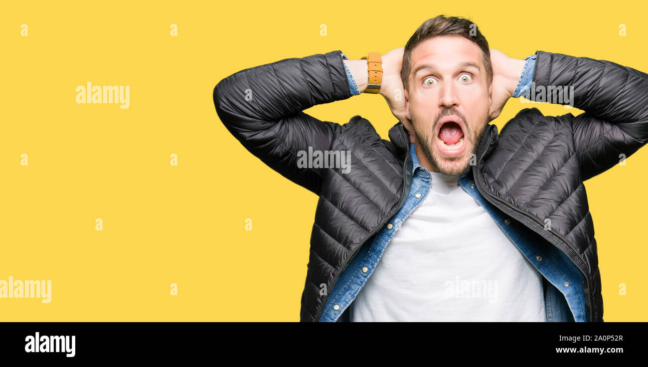 Handsome man wearing winter coat Crazy and scared with hands on head ...