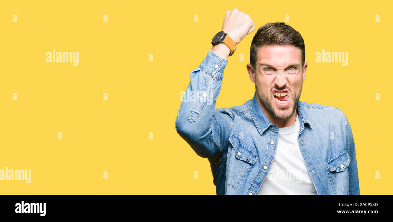 Handsome man with blue eyes and beard wearing denim jacket angry and ...