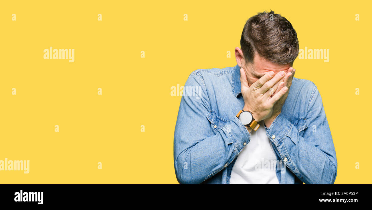 Handsome man with blue eyes and beard wearing denim jacket with sad ...