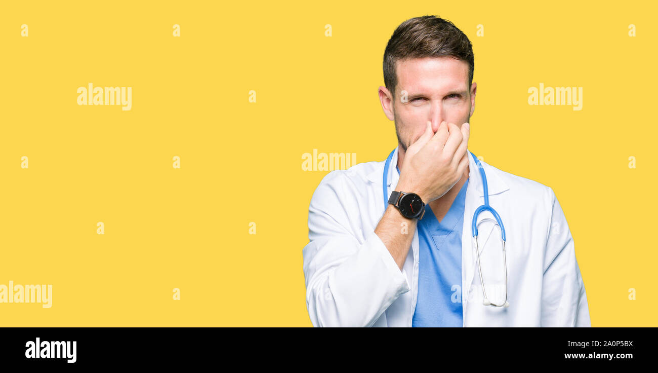 Handsome doctor man wearing medical uniform over isolated background ...