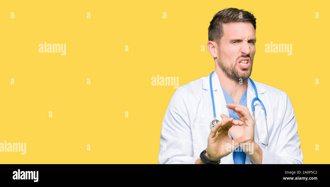 Handsome doctor man wearing medical uniform over isolated background ...