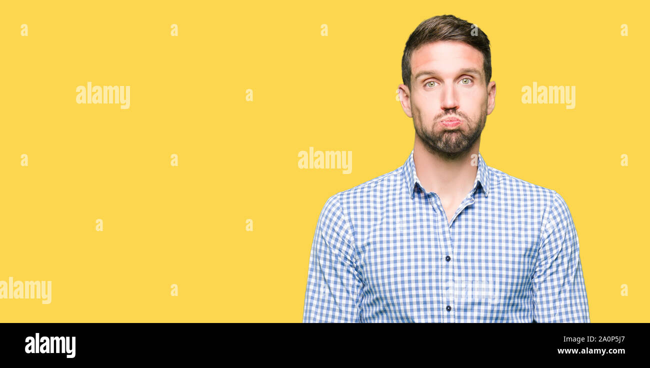 Handsome business man with blue eyes puffing cheeks with funny face ...