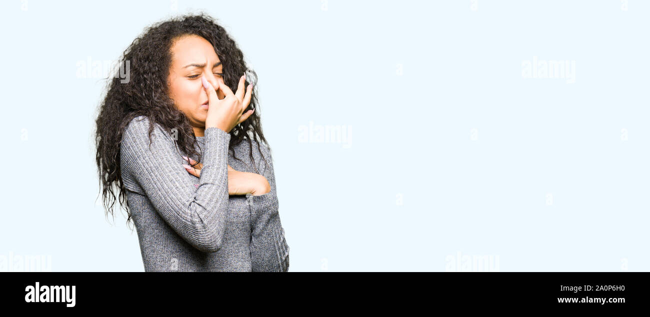 Young beautiful girl with curly hair smelling something stinky and ...