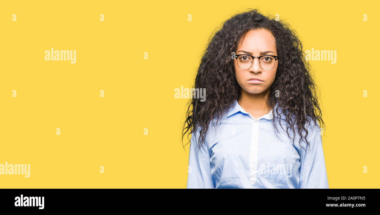 Young beautiful business girl with curly hair wearing glasses skeptic ...