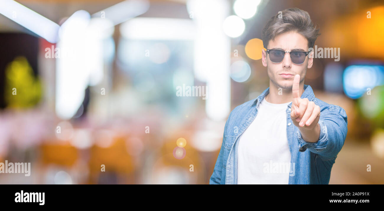 Young handsome man wearing sunglasses over isolated background Pointing ...