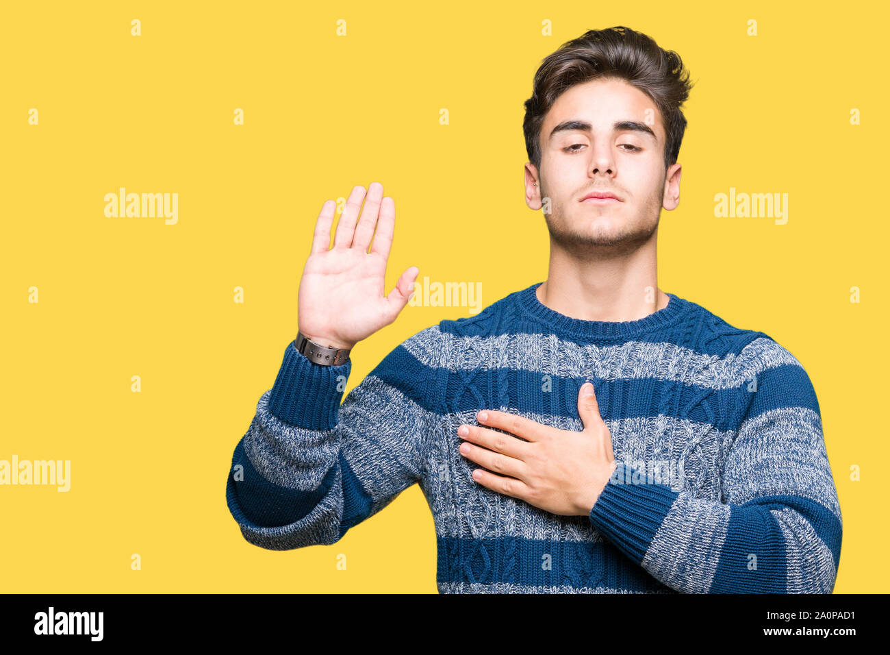 Young handsome man over isolated background Swearing with hand on chest ...