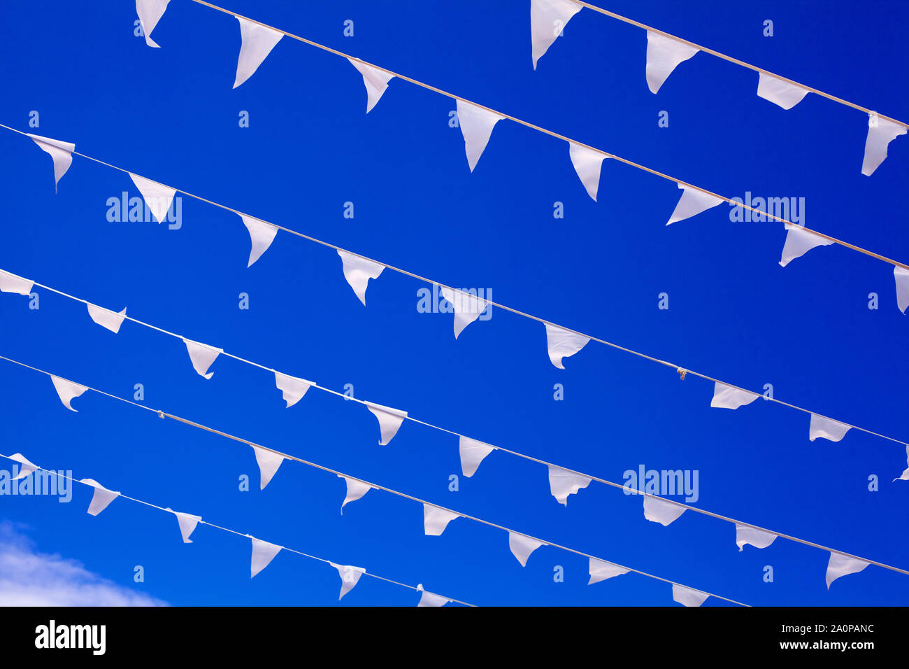 White triangular flags waving in wind blue sky background close up ...