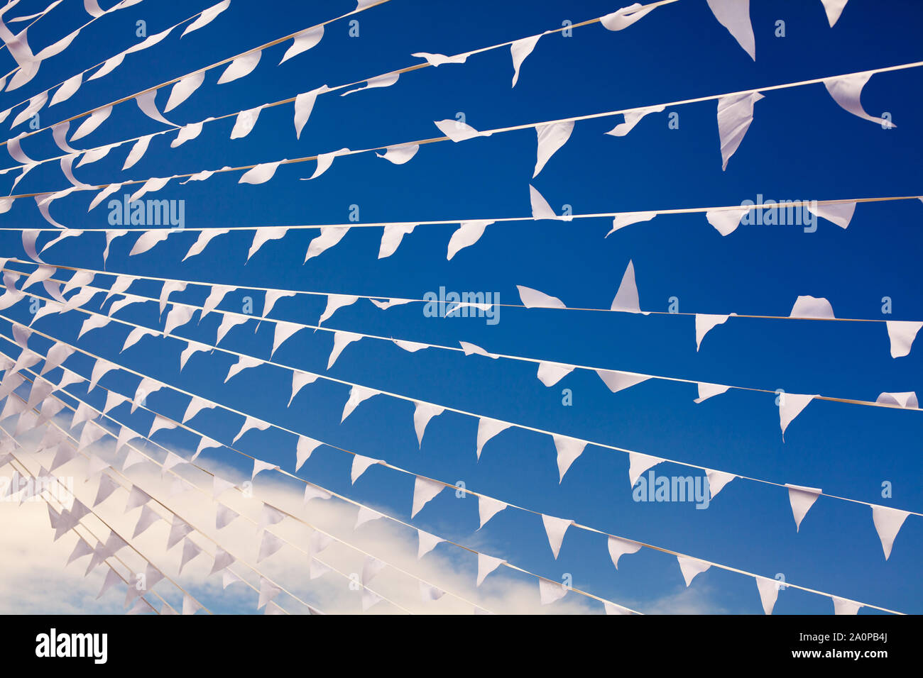 White triangular flags waving in wind blue sky background close up ...