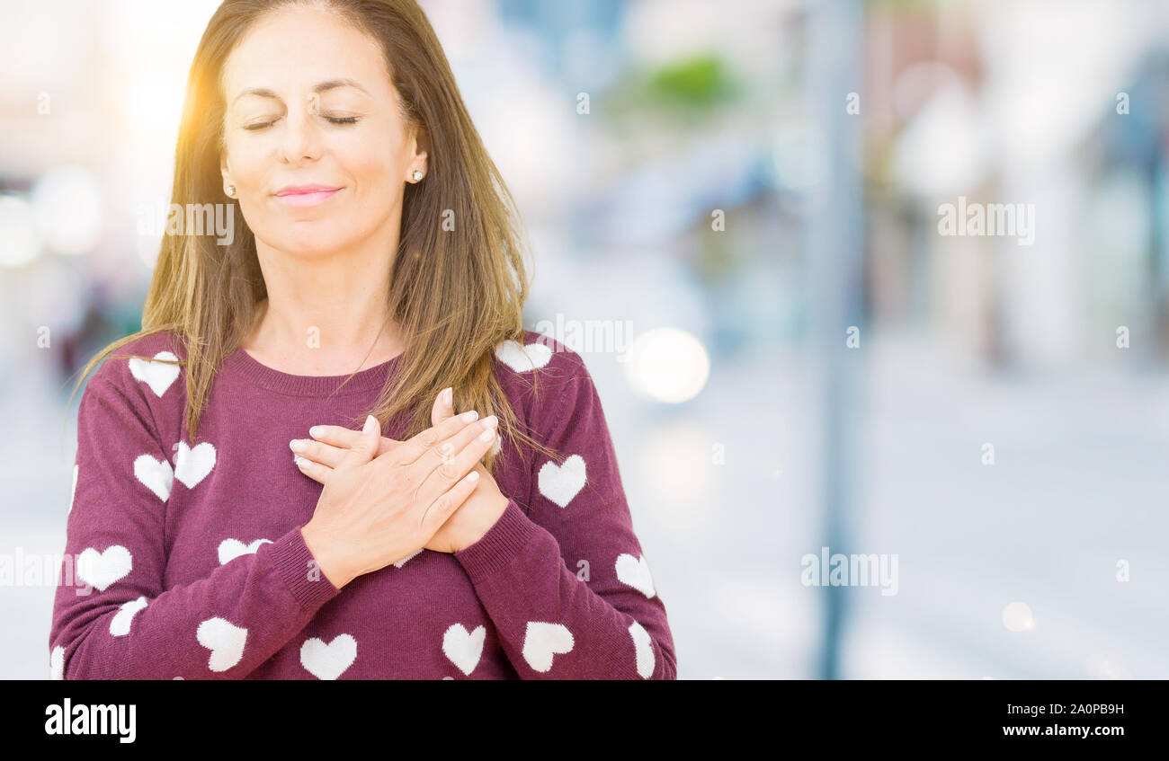 Beautiful middle age woman wearing hearts sweater over isolated ...