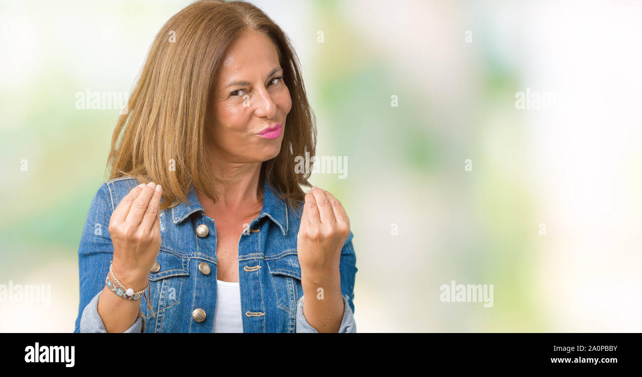 Beautiful middle age woman wearing casual denim jacket over isolated ...