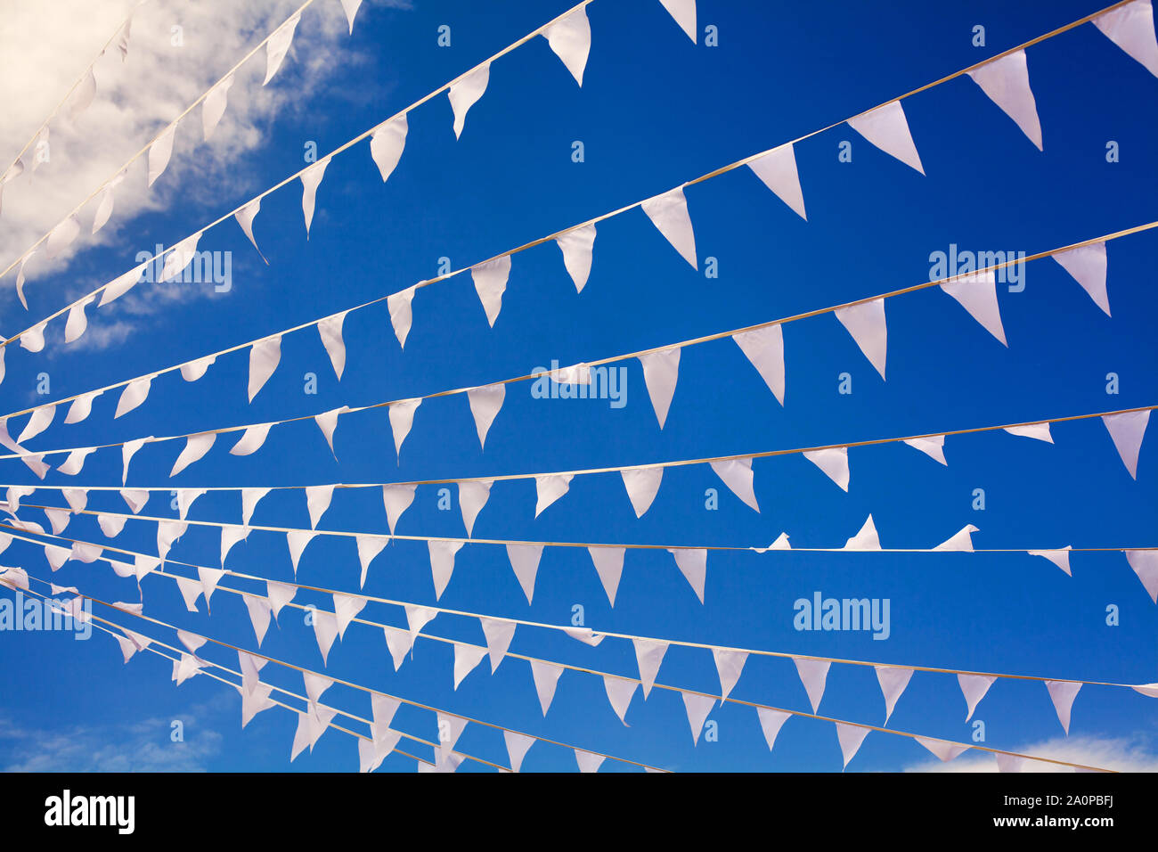 White triangular flags waving in wind blue sky background close up ...