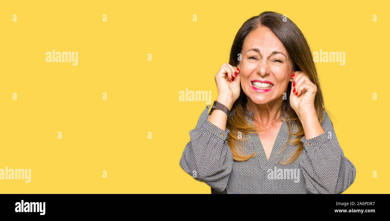 Beautiful middle age business woman covering ears with fingers with ...