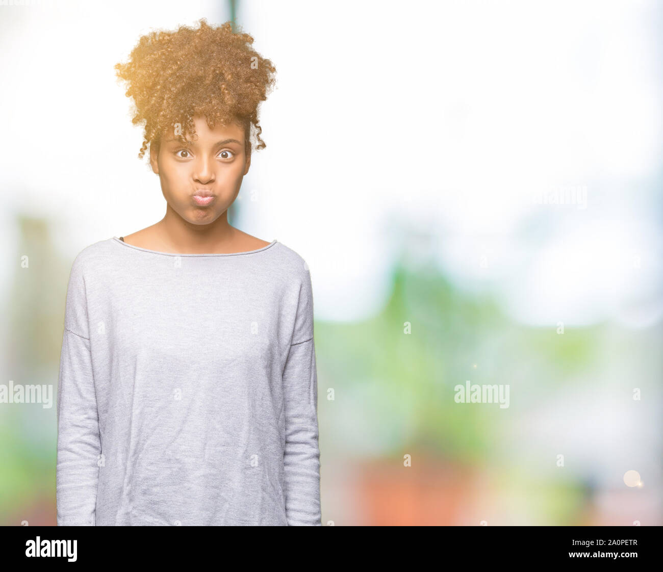 Beautiful young african american woman over isolated background puffing ...