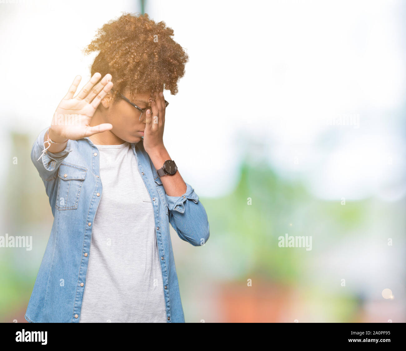 Beautiful young african american woman wearing glasses over isolated background covering eyes ...