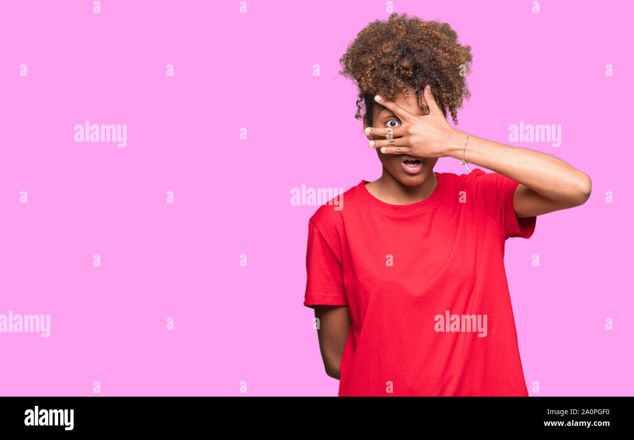 Beautiful young african american woman over isolated background peeking ...