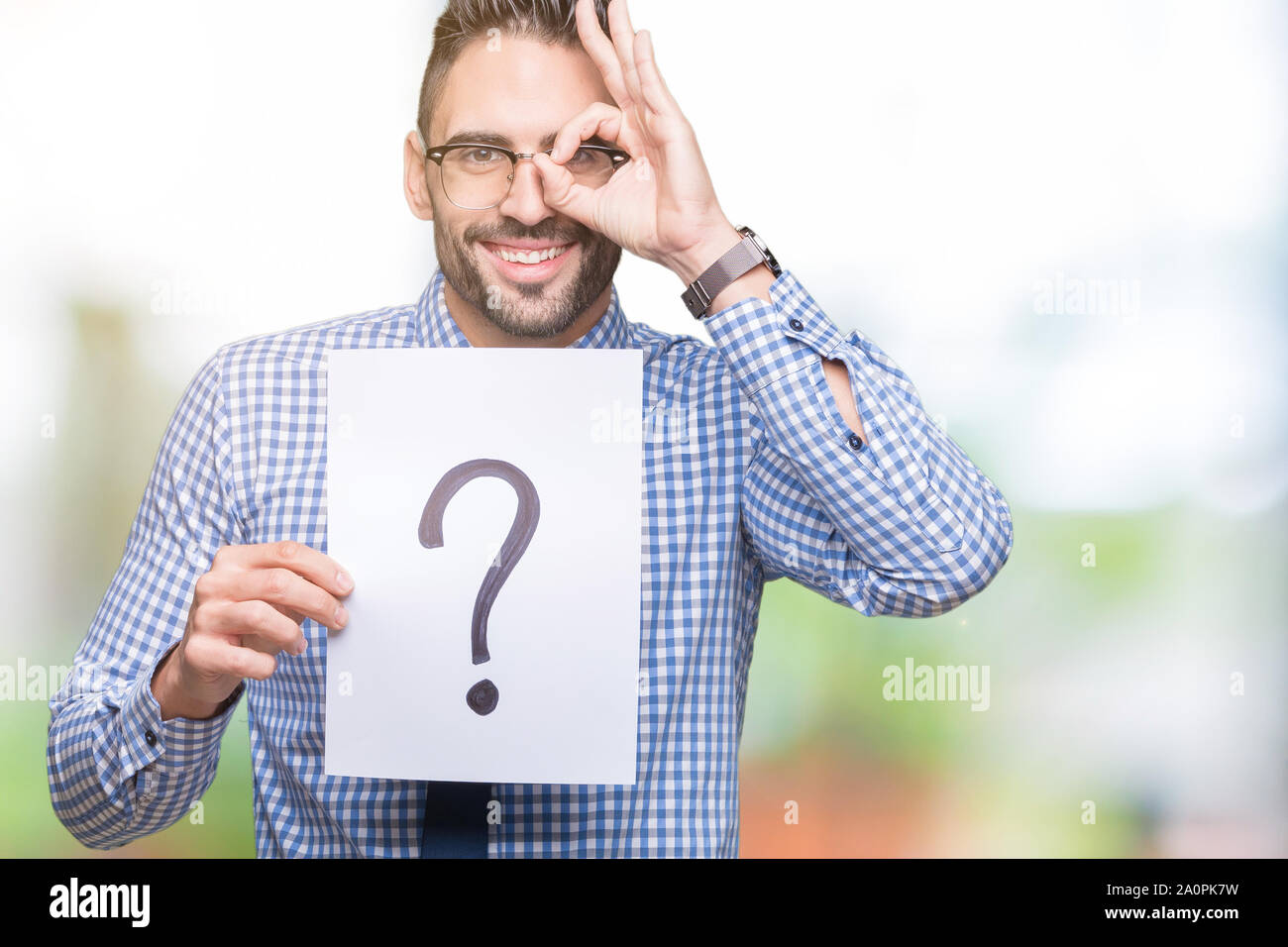 Handsome young business man holding paper with question mark over ...