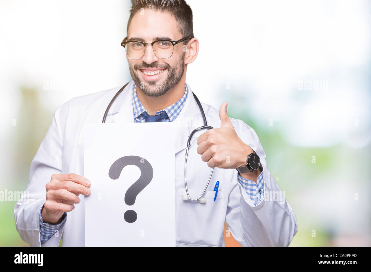 Handsome young doctor man holding paper with question mark over ...