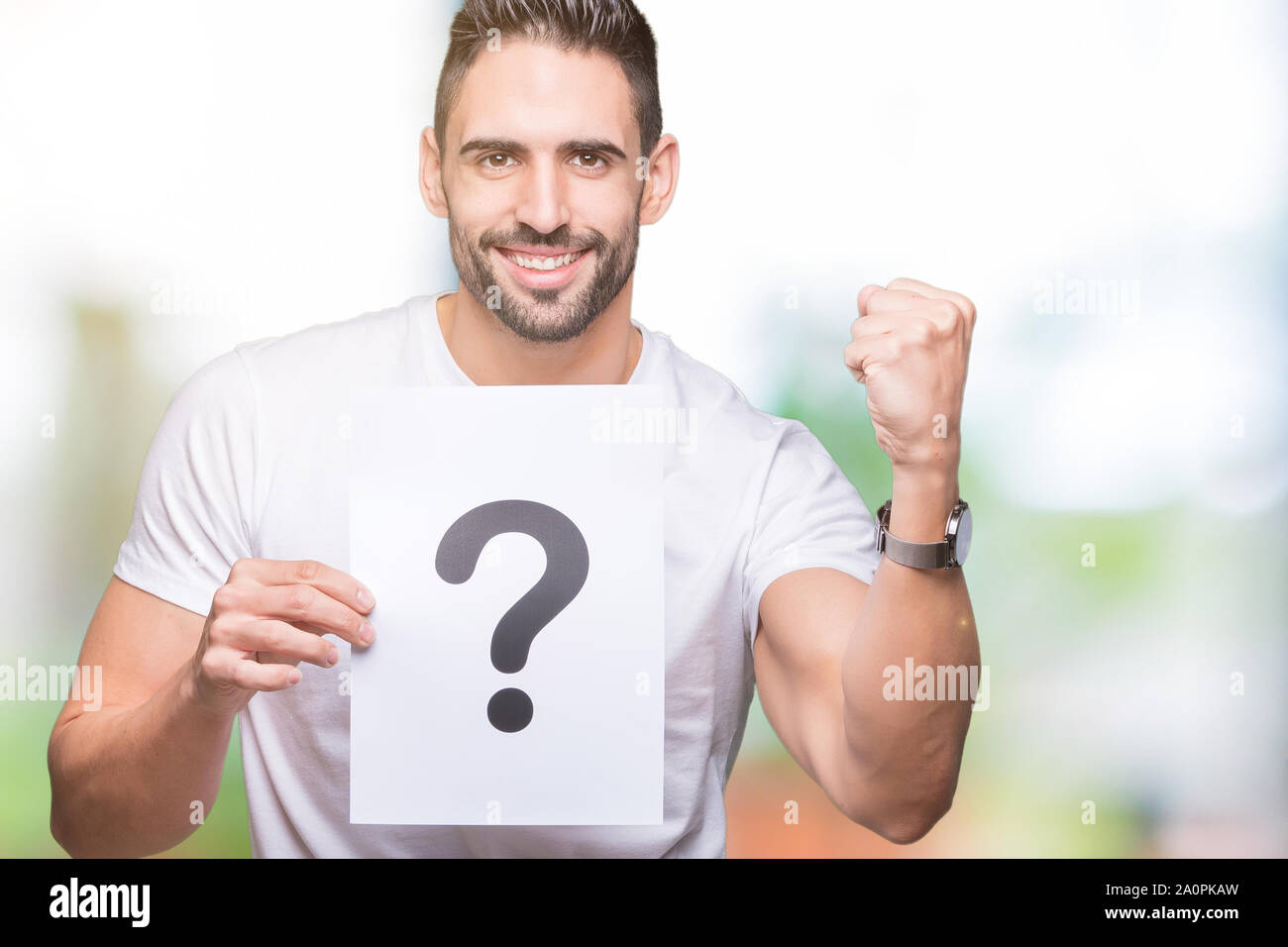 Handsome young man holding paper with question mark over isolated ...